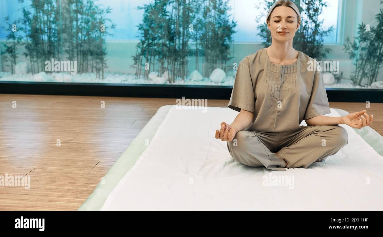 Attractive woman sitting in lotus pose or asana Padmasana on yoga mat ...