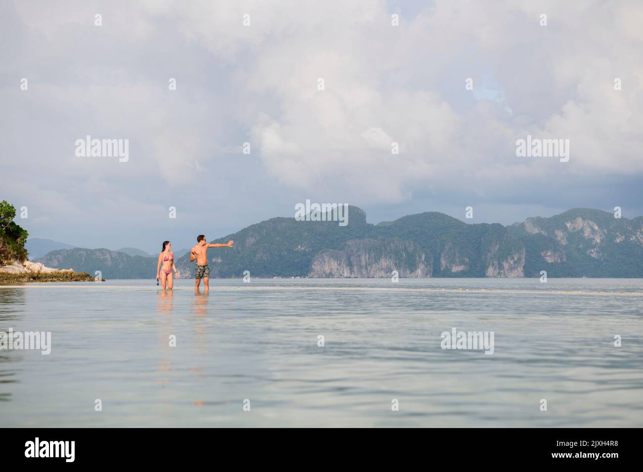 Couple walking on the beach in clear sea water in Asia. Exploring the ...