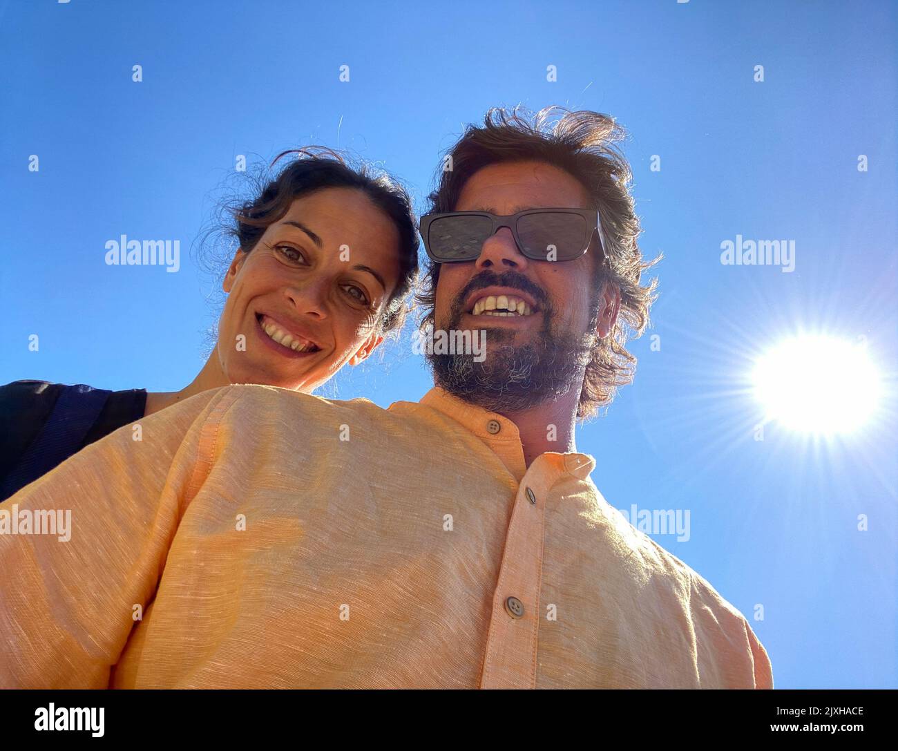 A tourist couple taking a selfie with a smiling smartphone with the sun ...
