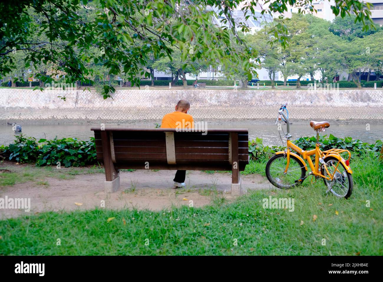 Elderly person enjoys sitting on the park bench after riding his orange ...
