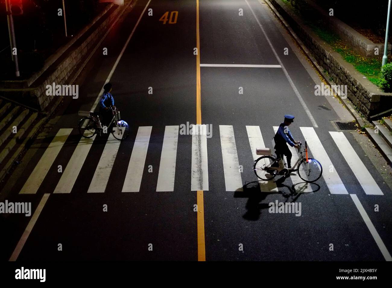 Japanese police couple on bicycles crossing crosswalk at night Stock ...