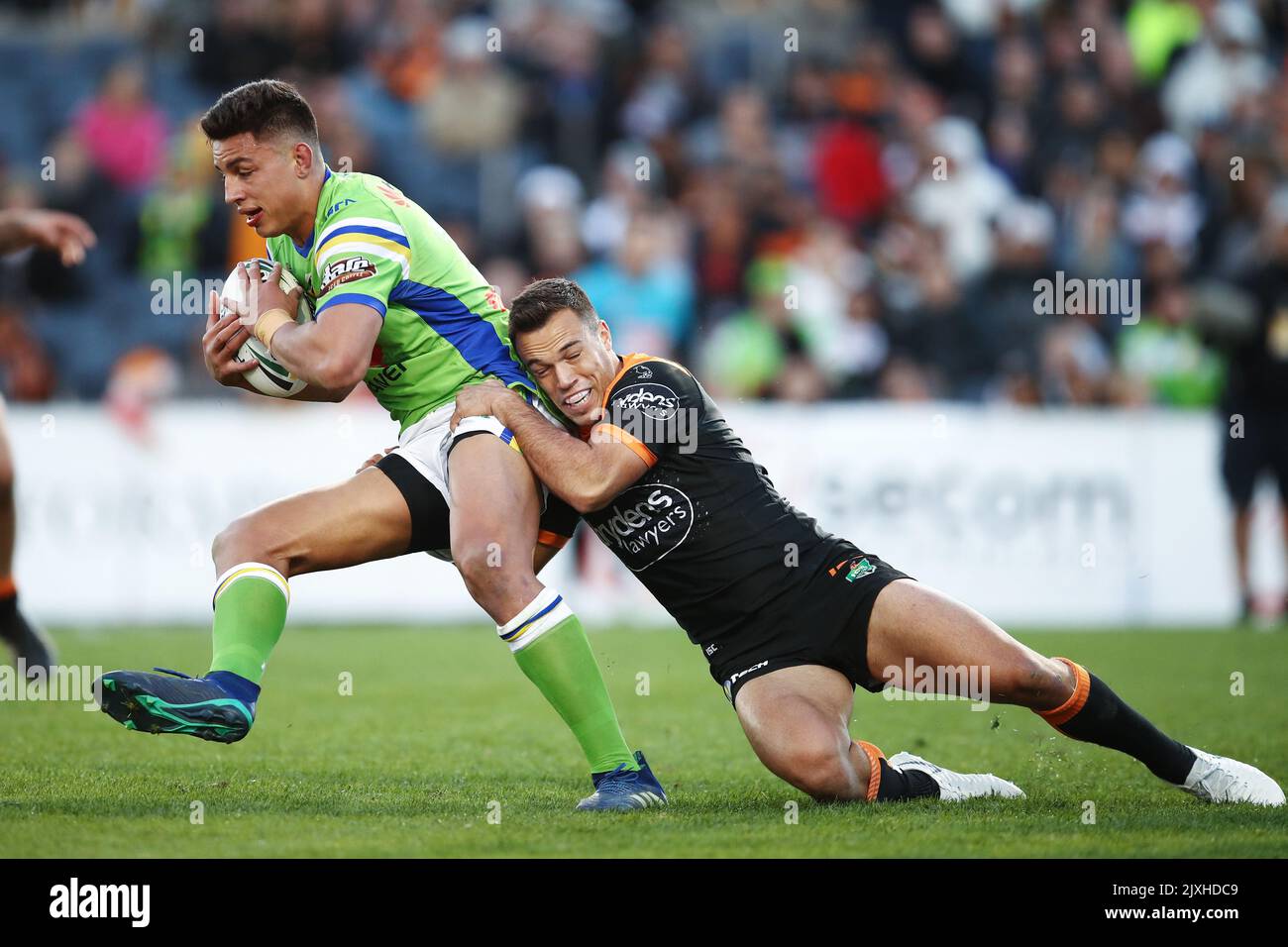 Joseph Tapine of the Raiders is tackled by Luke Brooks of the Tigers ...