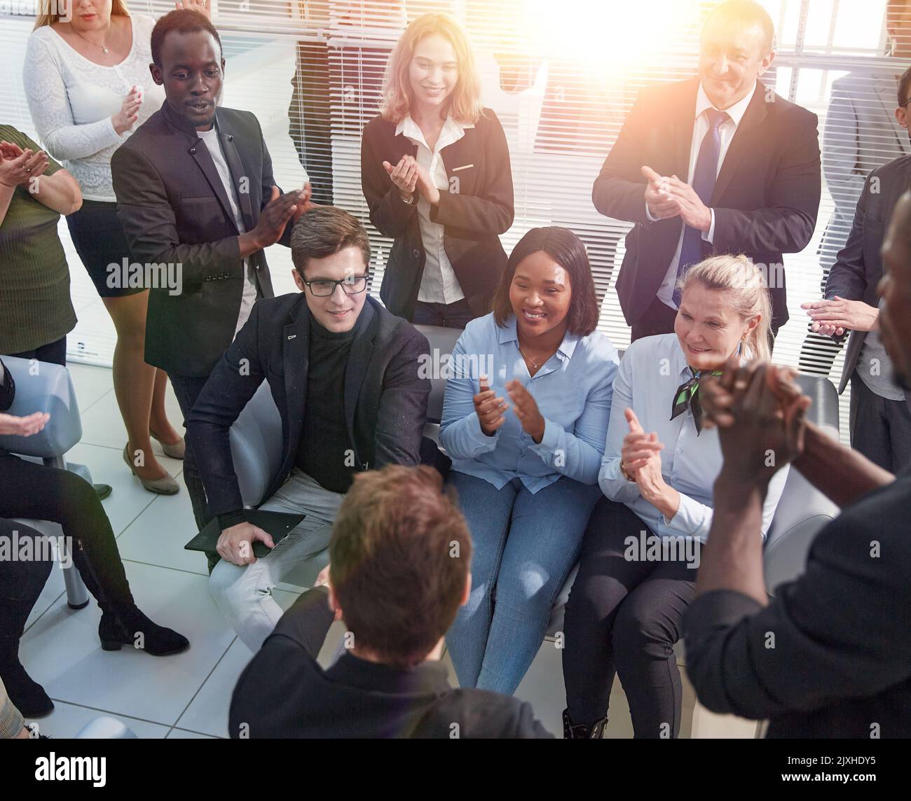 Office employees sit on chairs clap hands greeting presenter or speaker ...