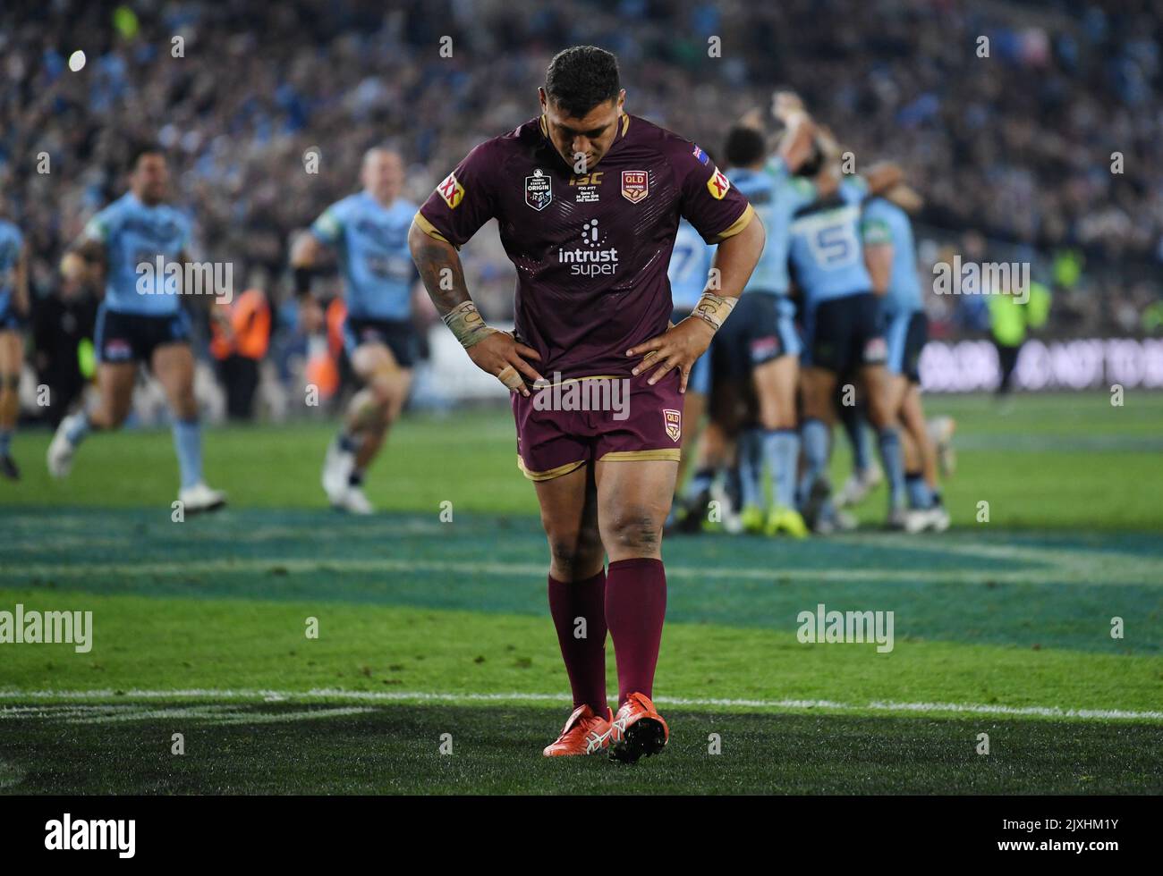 Josh Papalii of the Maroons looks down as NSW Blues players celebrate ...