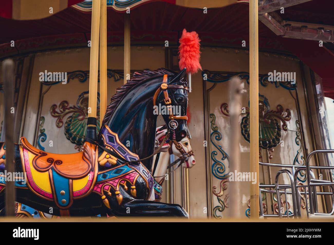 The view of a Merry go round carousel black horse with red feathers on ...