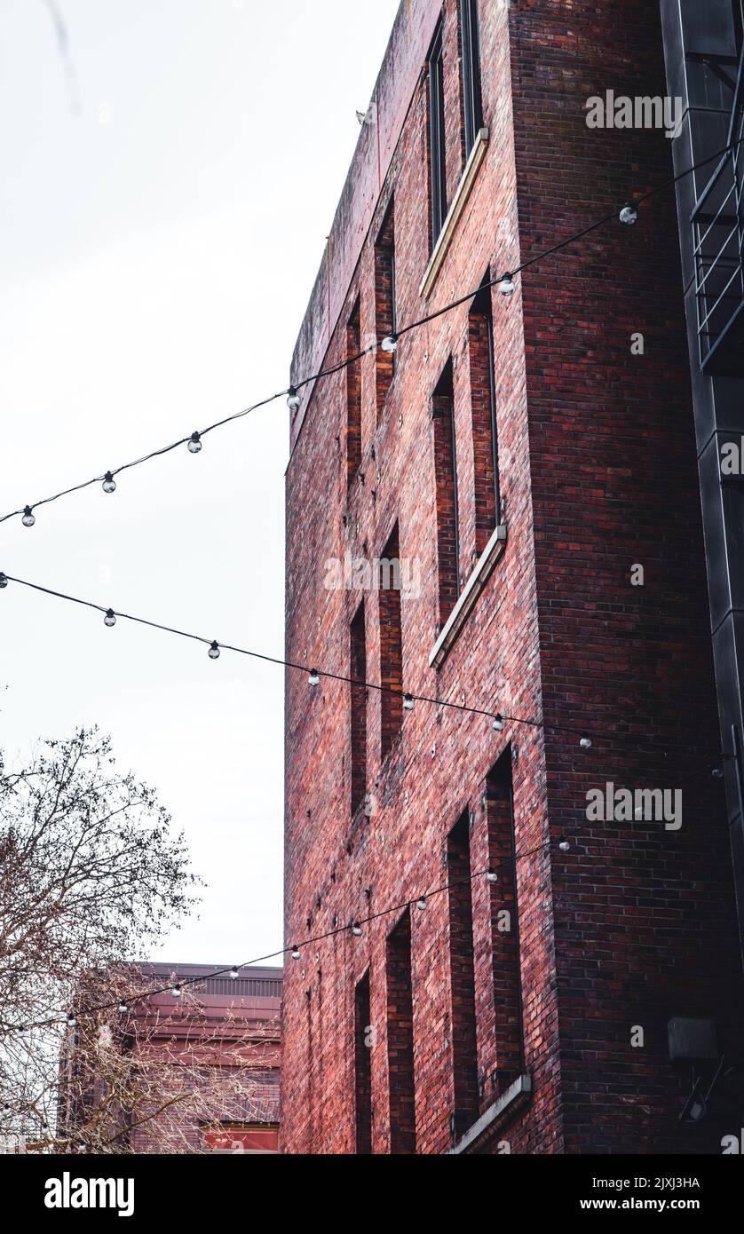 A vertical shot of red brick apartment building with hanging lights in ...
