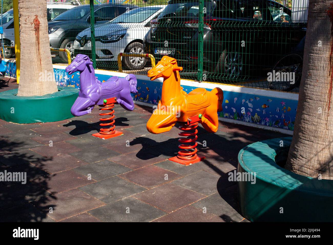 Colorful swing in shape of horse for children in playground on rubber ...