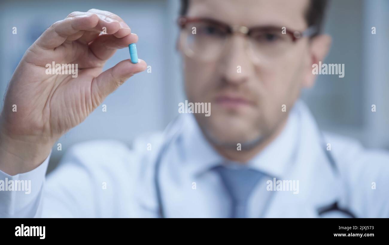 blurred doctor in glasses and white coat looking at camera and holding ...