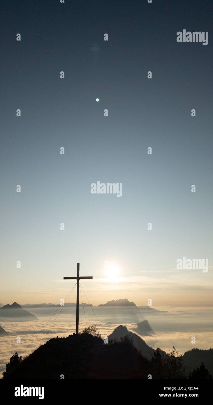 A vertical shot of the silhouette of a cross on top of the hill against ...