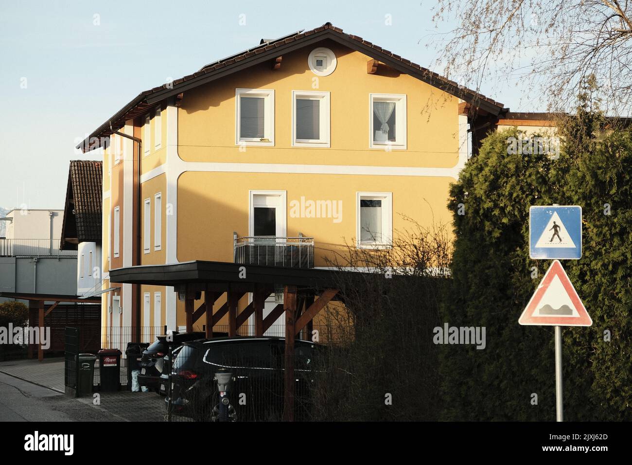A residential building with road signs for pedestrian crossing and hump ...
