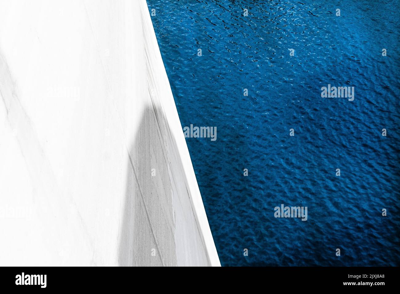 A white wall and smooth blue water surface Stock Photo - Alamy