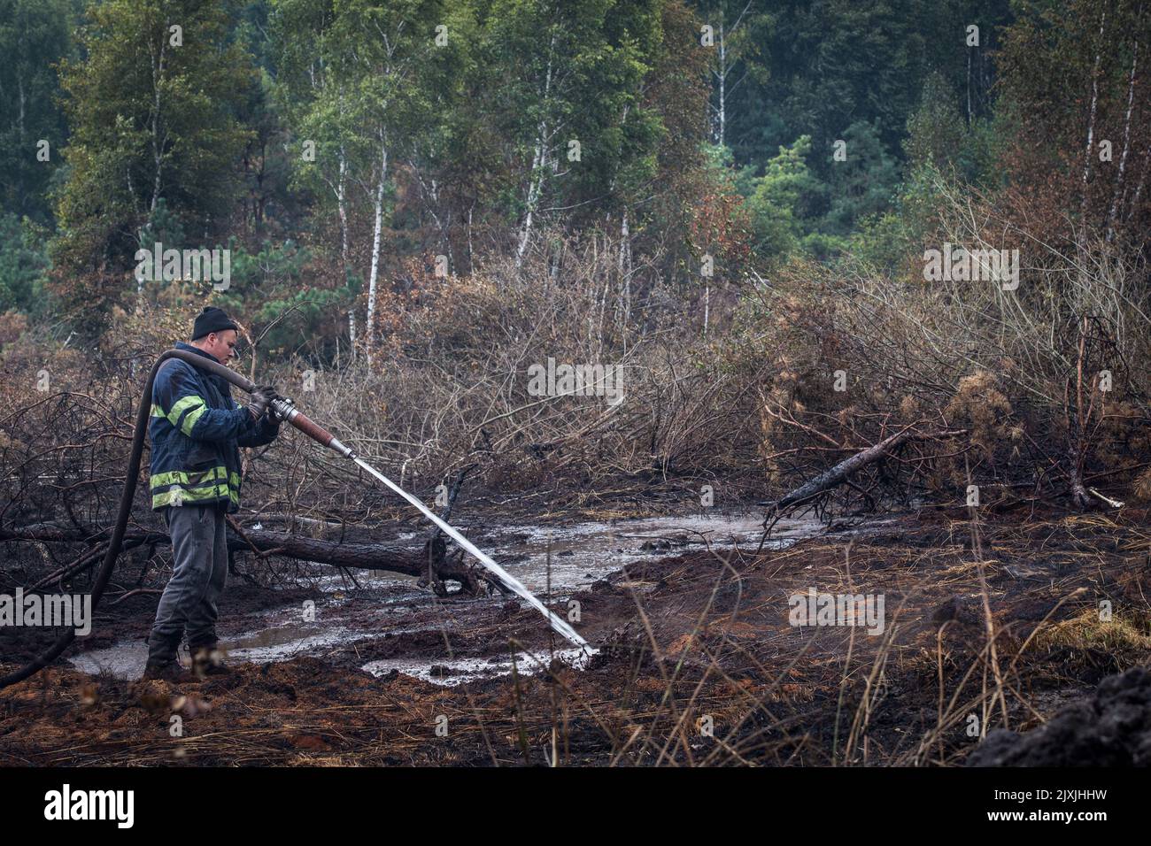 A firefighter puts out a fire in a peat bog in the village of Sosnivka ...