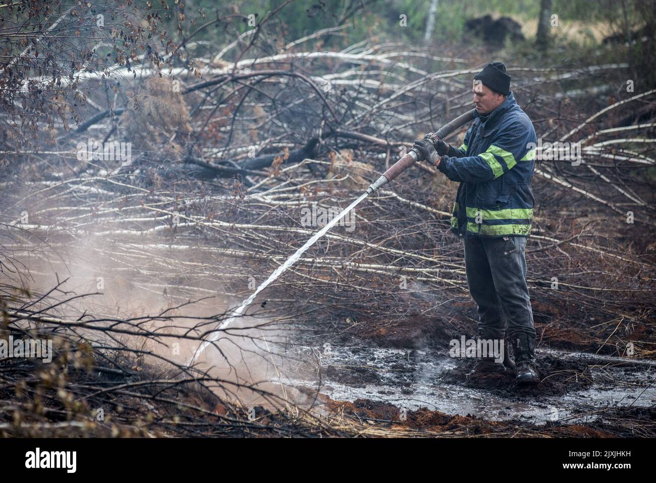 A firefighter puts out a fire in a peat bog in the village of Sosnivka ...