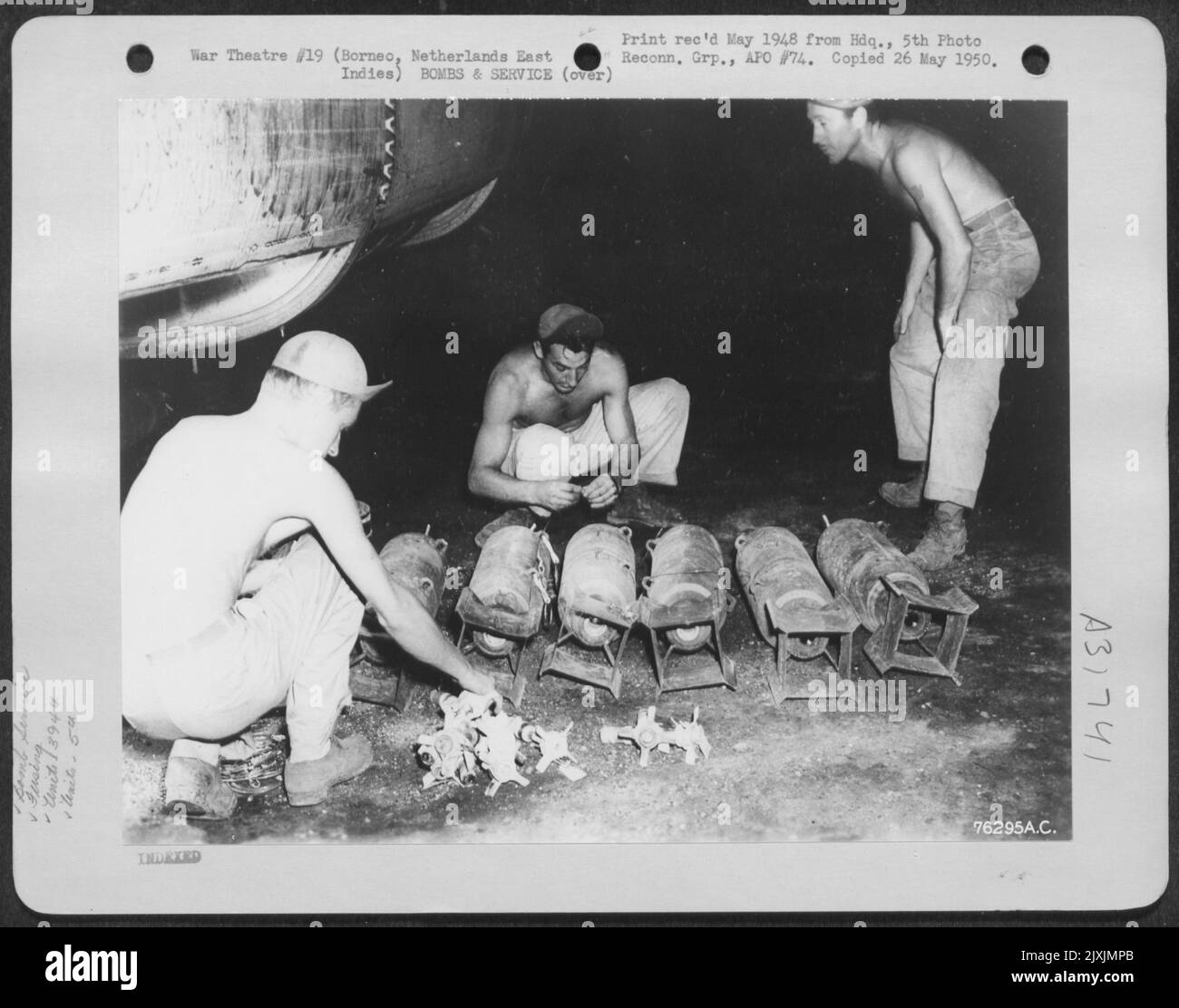 Armament men insert fusese into bombs prior to loading into an airplane ...