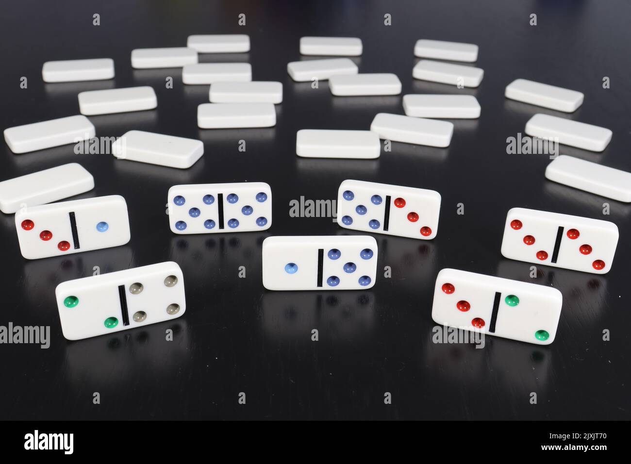 White domino pieces with colored dots over a black wood table Stock ...