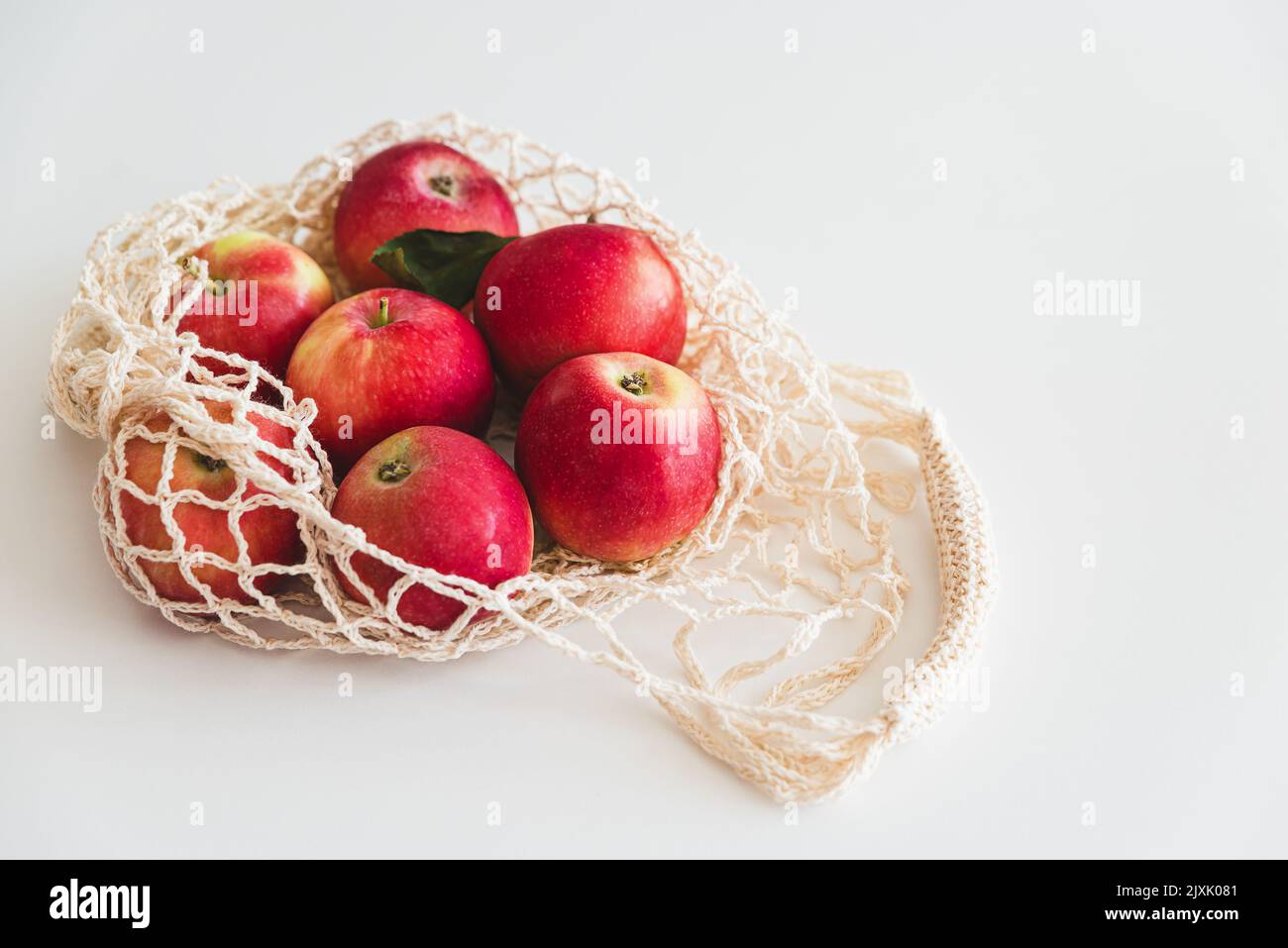 String bag with red ripe apples on white background. Top view Stock ...
