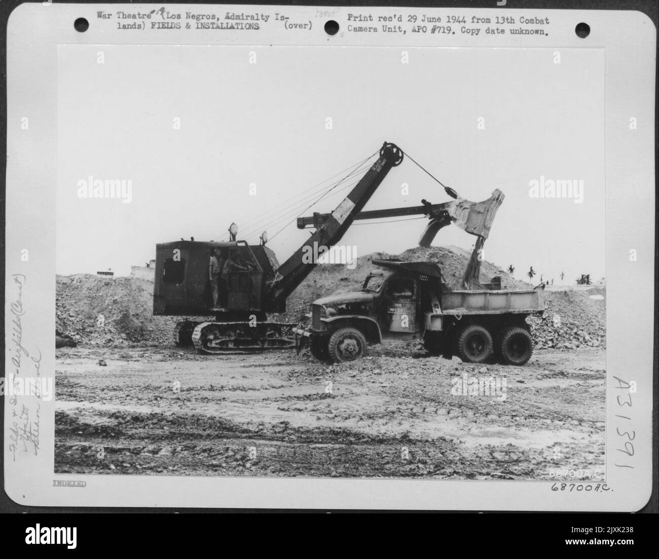 A steam shovel loads a dump truck with coral at the pit on Los Negros ...