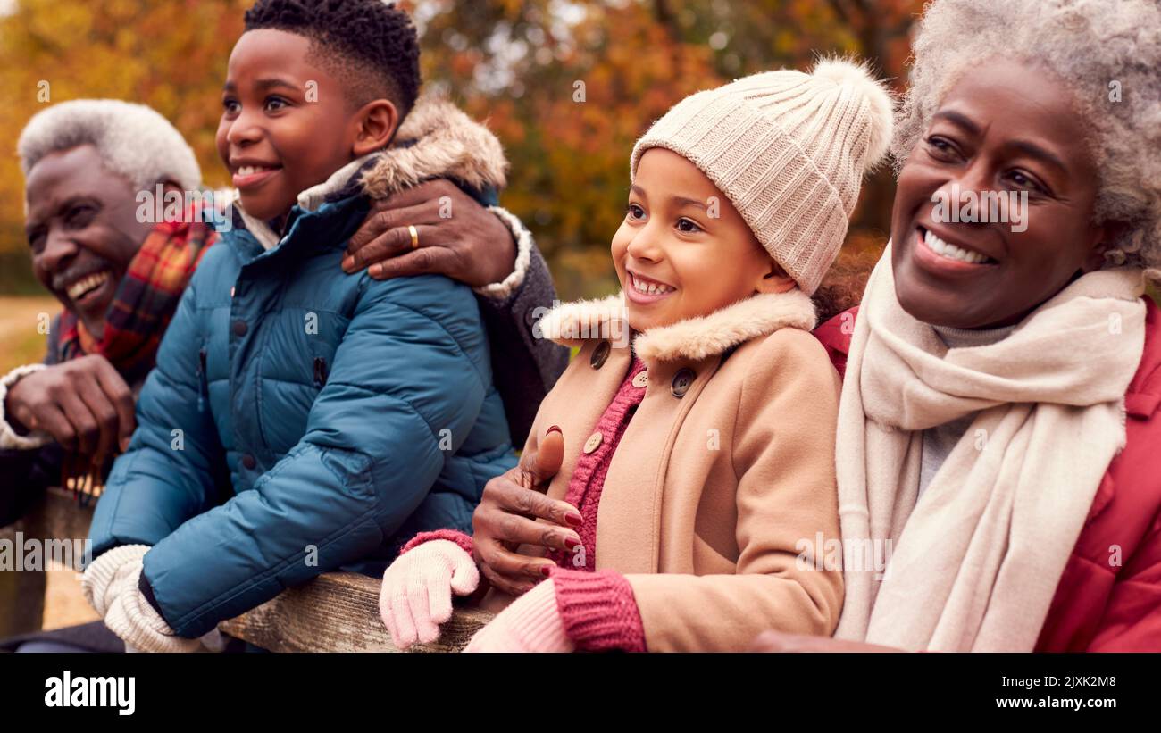 Grandparents By Gate With Grandchildren On Walk Through Autumn ...