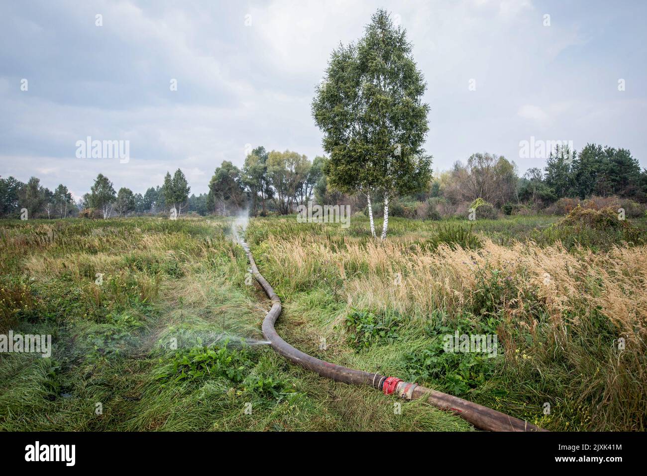 A damaged water hose overflowing with water from a river to put out a ...
