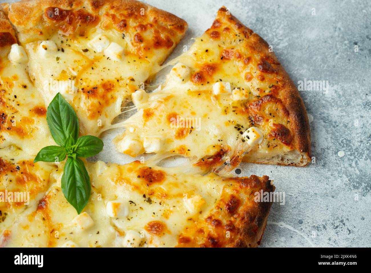Italian pizza four cheeses with stretching cheese and basil on a light ...