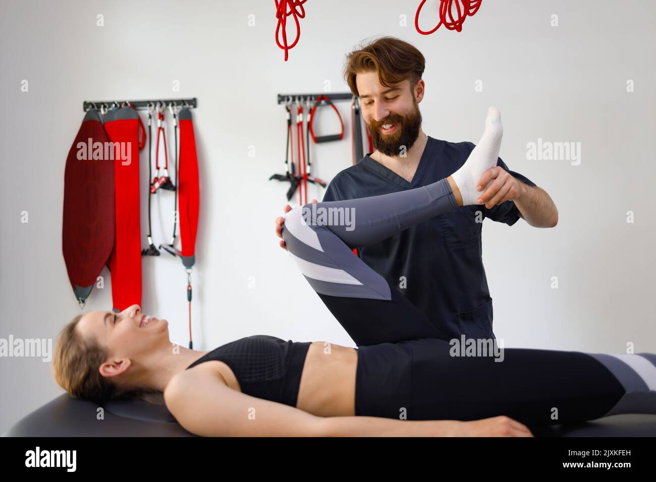 Side view of a cheerful physiotherapist doctor and his female patient ...