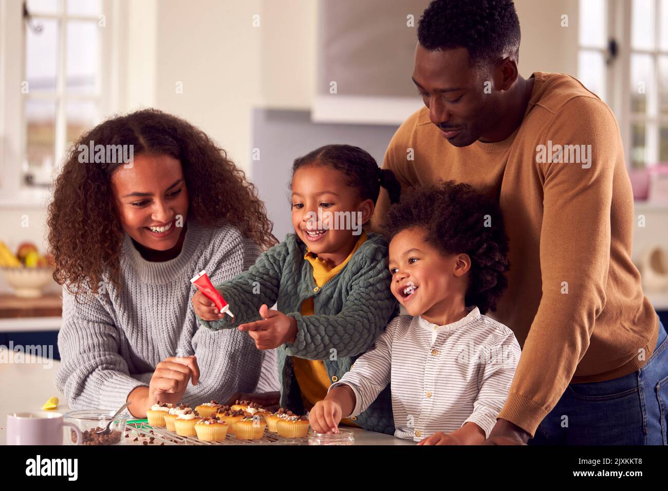 Family Baking Cupcakes Sitting Around Kitchen Counter At Home Stock ...