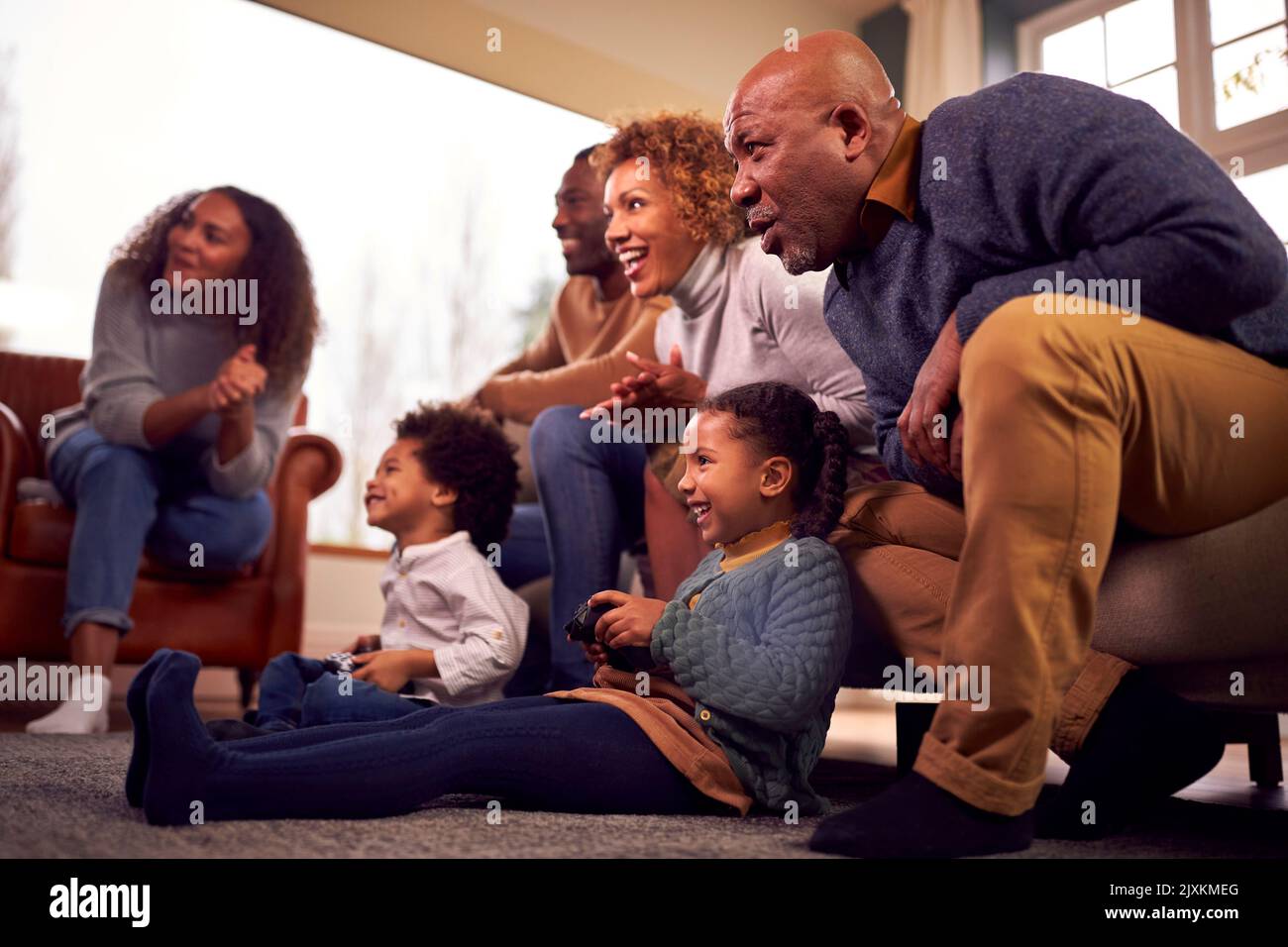 Multi-Generation Family Having Fun Playing Video Game In Lounge At Home ...