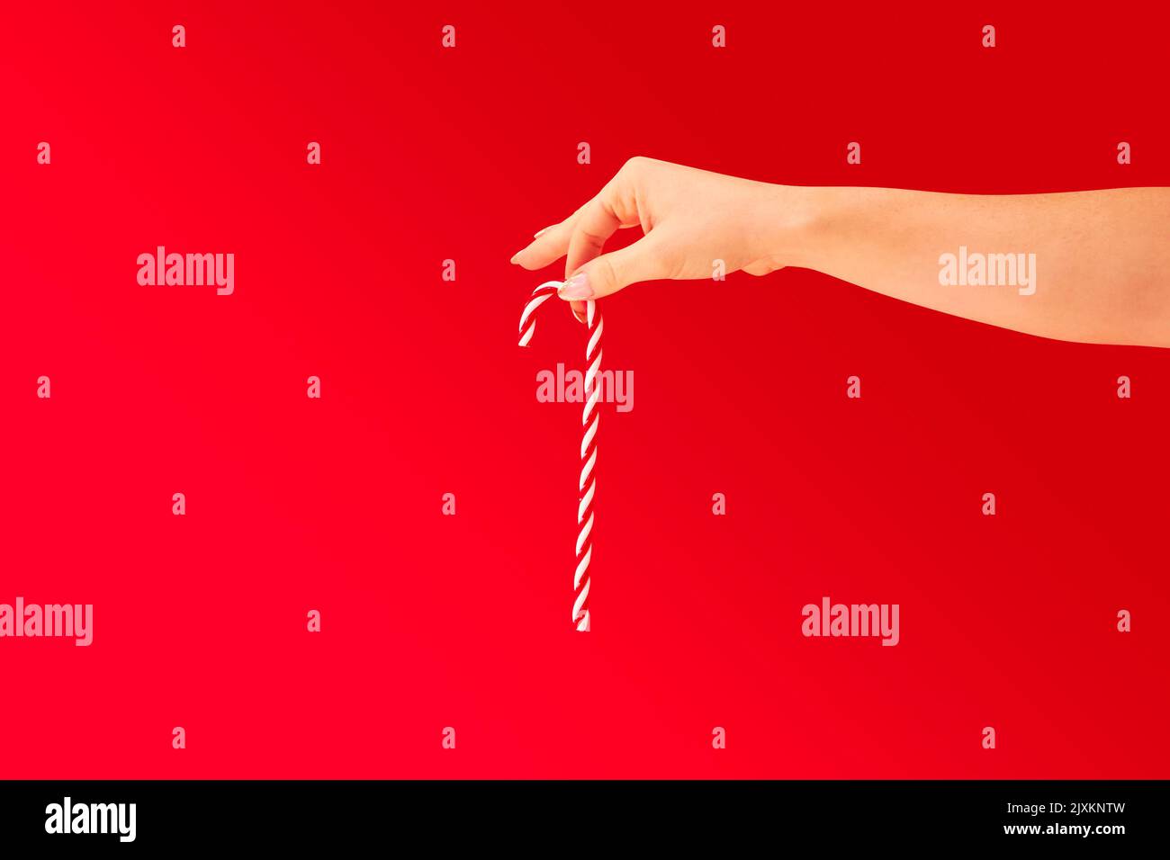 Close Up Studio Shot Of Woman Holding Christmas Candy Cane Against Red ...