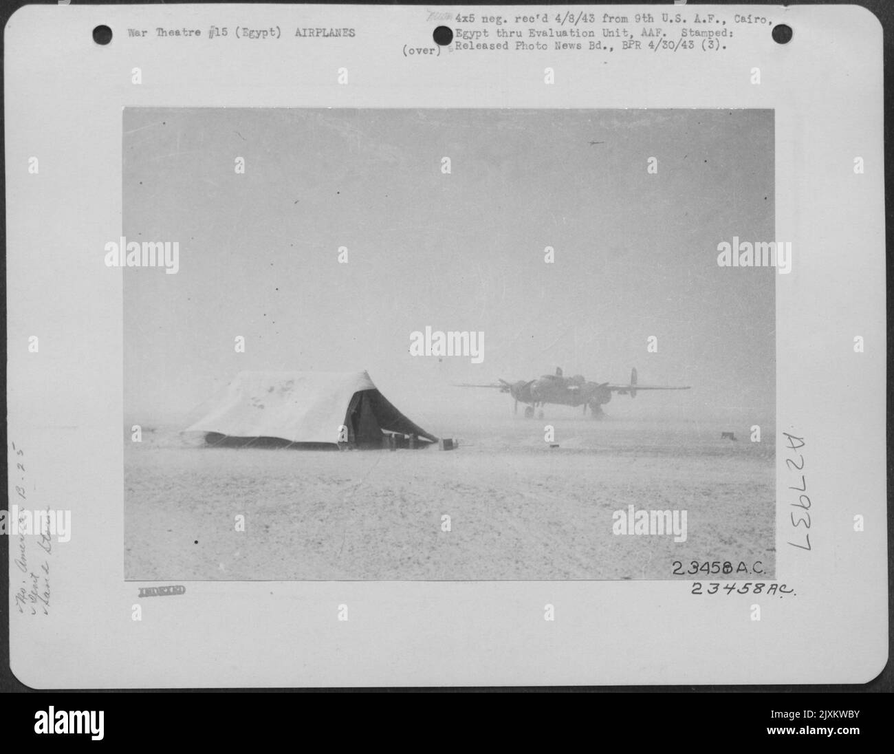On a desert in Egypt, a North American B-25 is hardly visible through a ...