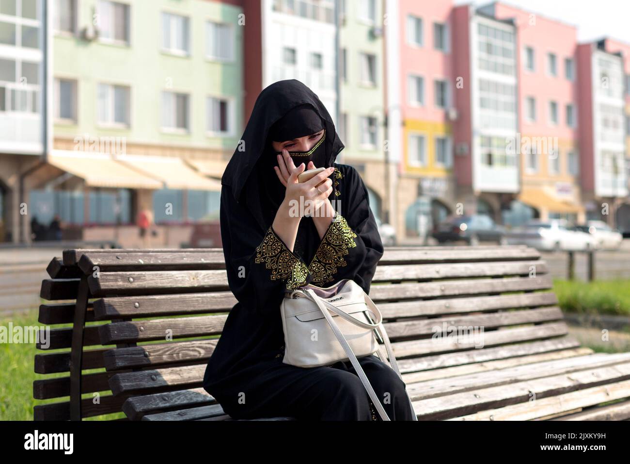 A Muslim woman is resting on a bench in the park, tidying herself up ...