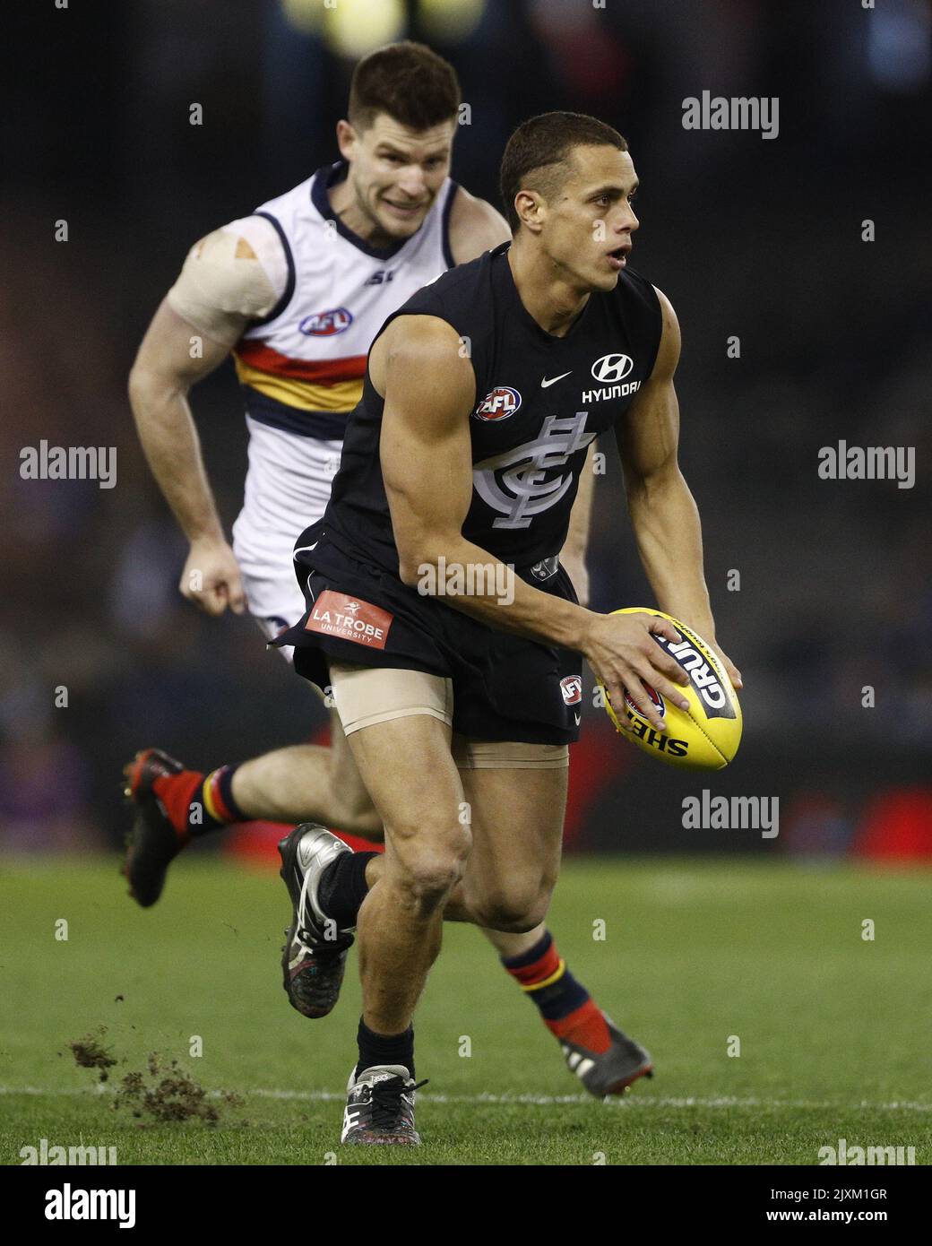 Ed Curnow of the Blues runs with the ball under pressure from Bryce ...