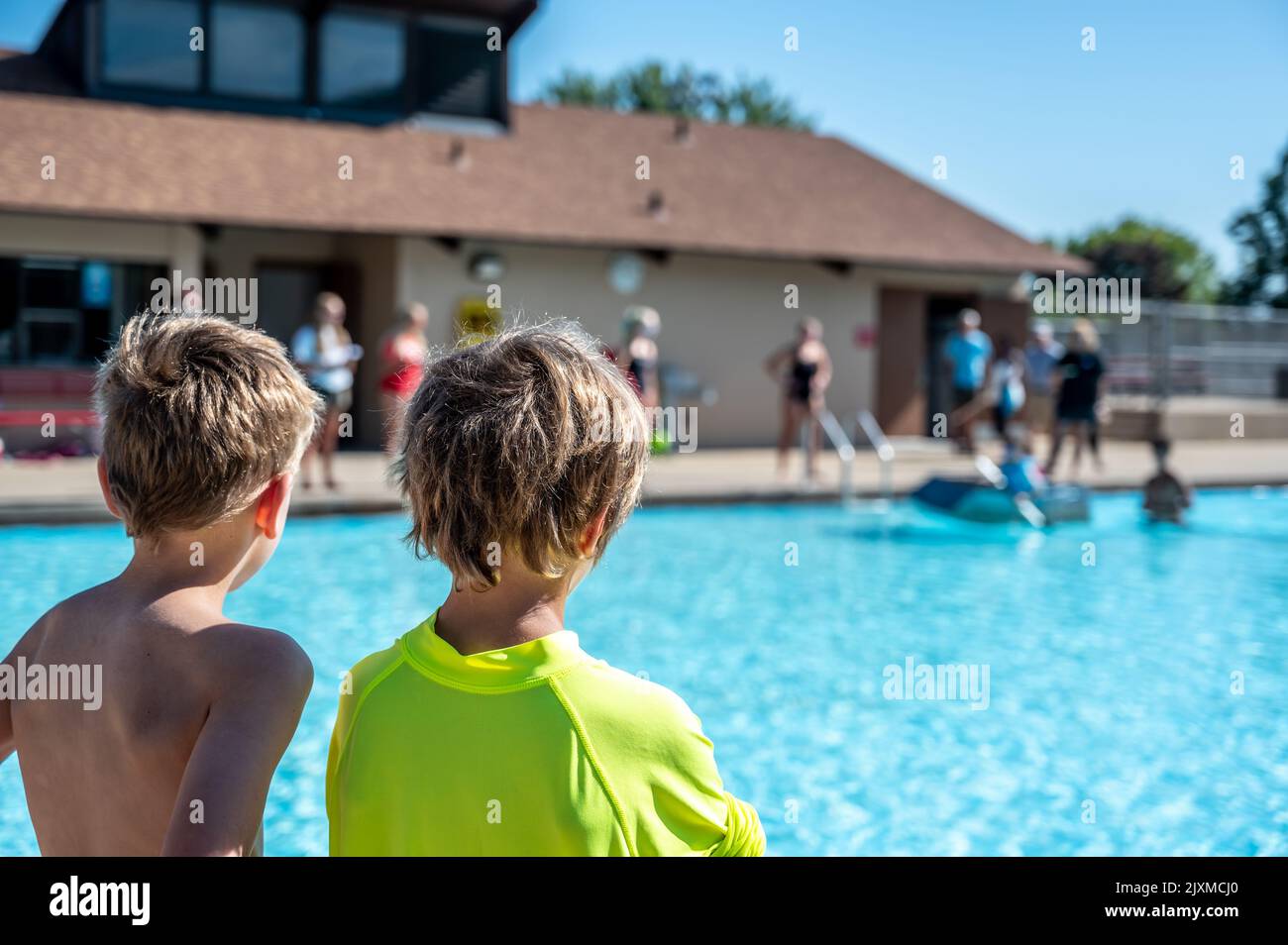 Two boys looking towards a cardboard boat floating in a pool Stock ...