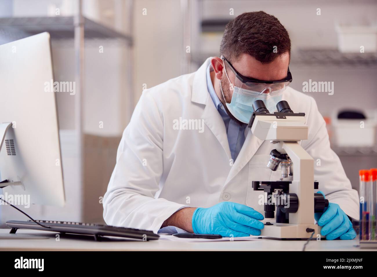 Male And Female Lab Workers Conducting Research Using Microscope And ...
