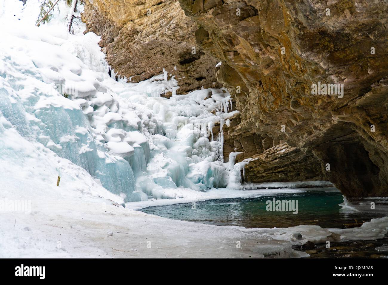 A beautiful scenery of a frozen waterfall leading down to small cave ...
