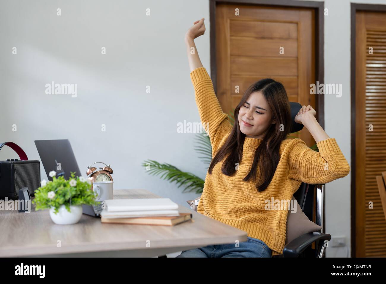 Happy businesswoman warming up body and muscles at workplace, feeling satisfied with work done ...