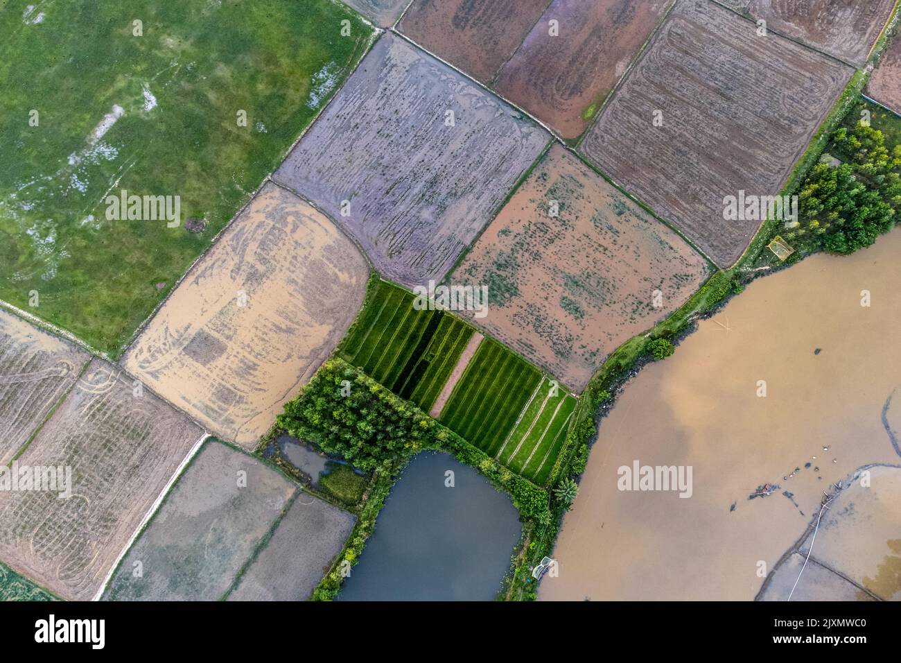 Aerial view of a green field with a small river Stock Photo - Alamy