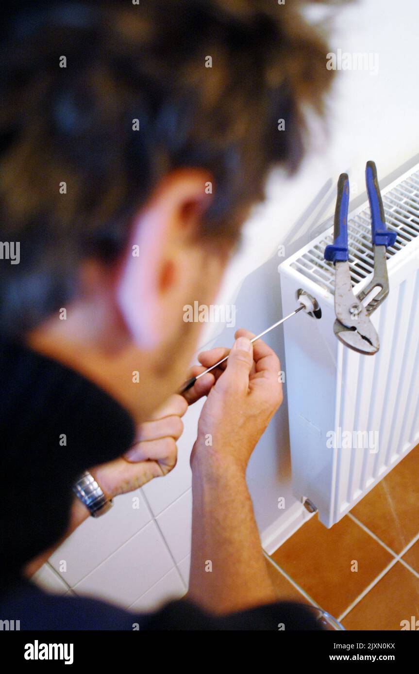 Man with screwdriver fixing radiator. Close-up of male repairing ...