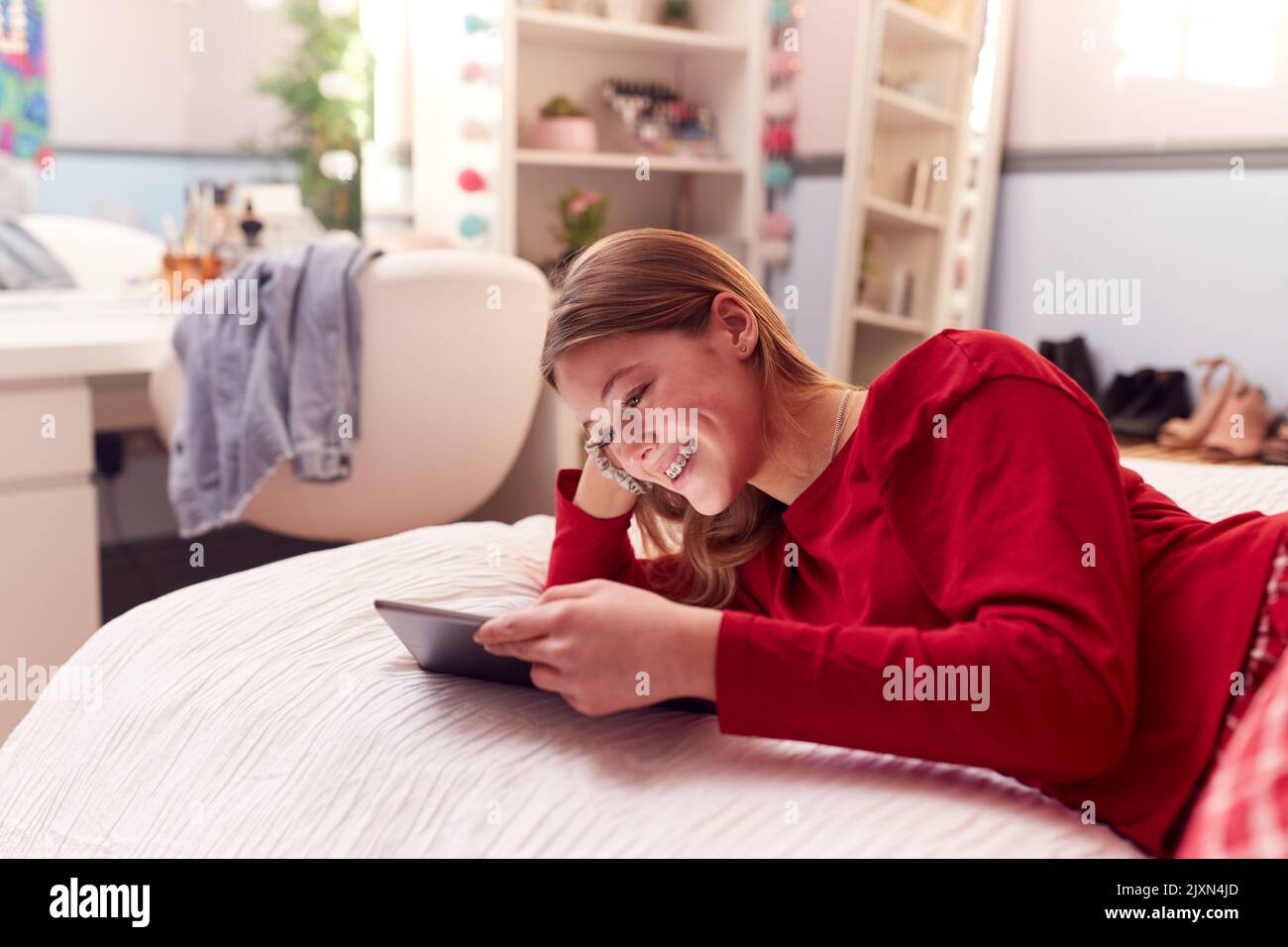 Teenage Girl Wearing Orthodontic Braces Lying On Bed At Home Using ...