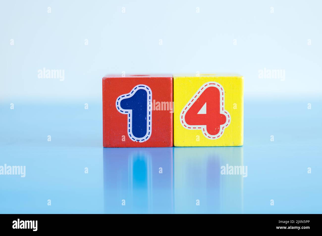 A blue number 1 on a red wooden block and red number 4 on a yellow ...