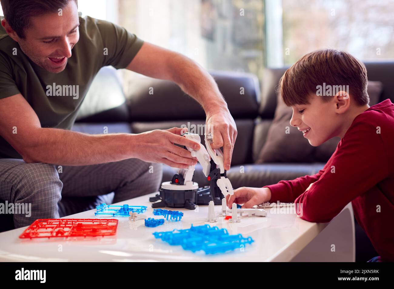 Father And Son Wearing Pyjamas Building Robotic Arm From Plastic Kit At ...