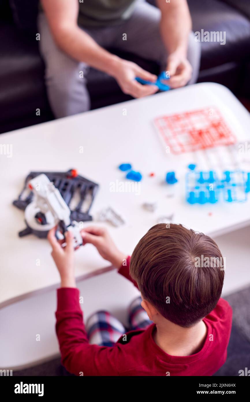 Father And Son Wearing Pyjamas Building Robotic Arm From Plastic Kit At ...