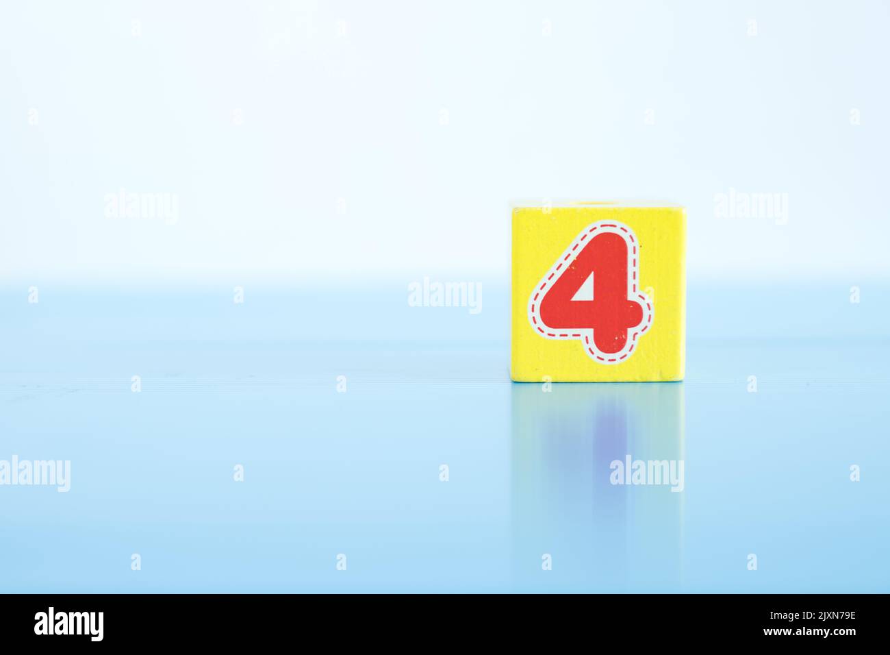 A yellow cube with the number 4 on it isolated on a blue gradient ...