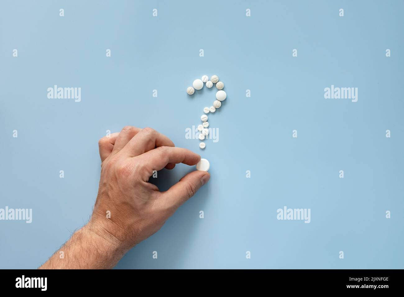 Hand laid out the pills in the form of a question mark, on a blue ...
