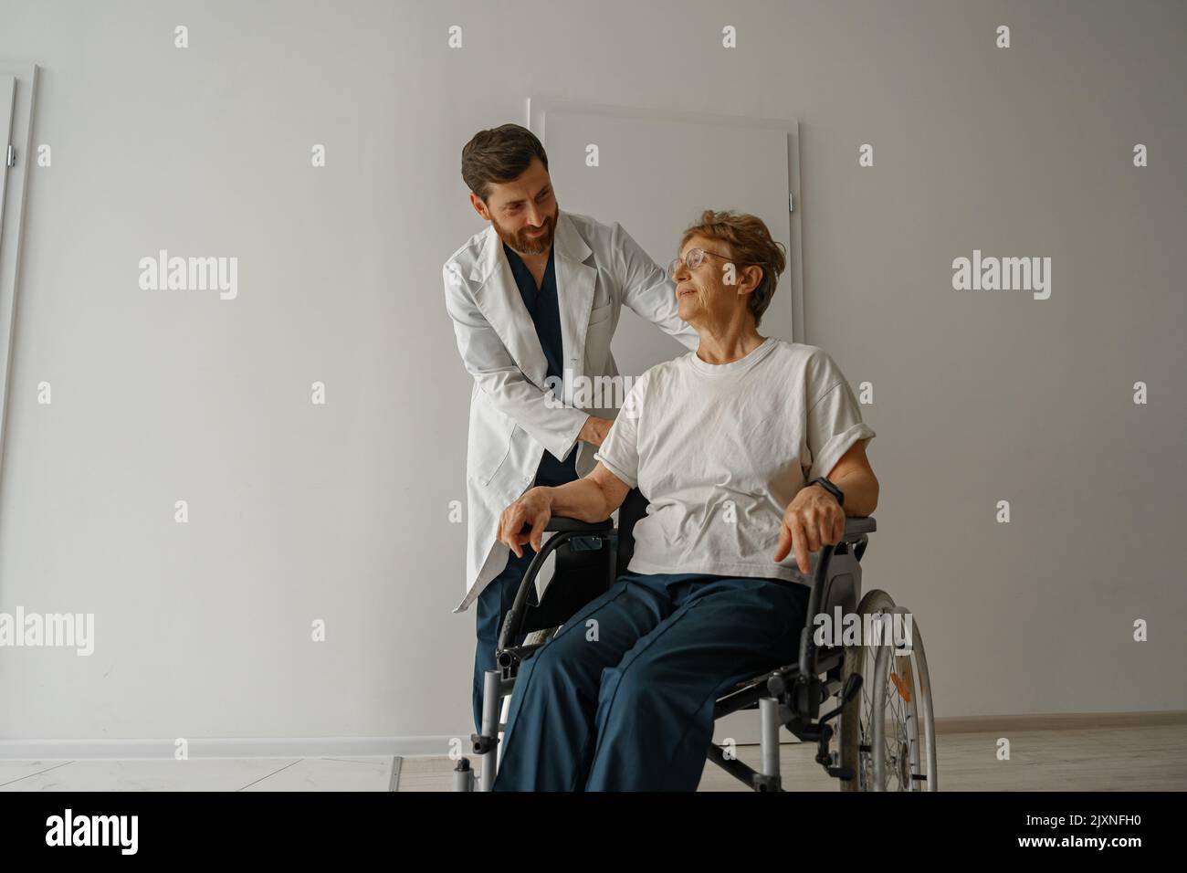 Professional male doctor carrying female patient on wheelchair in ...