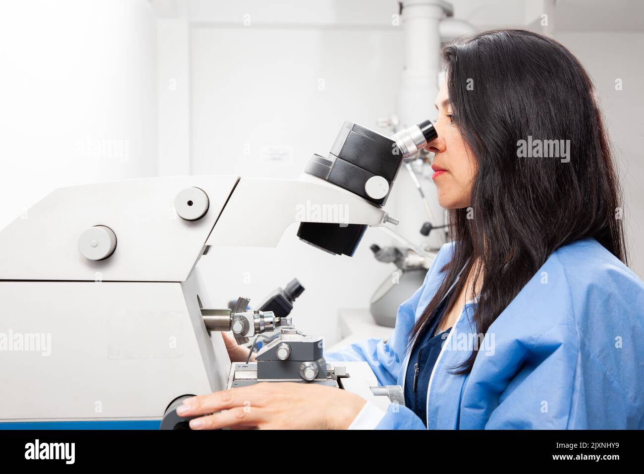 Young female scientist using an ultramicrotome to make sections for the ...