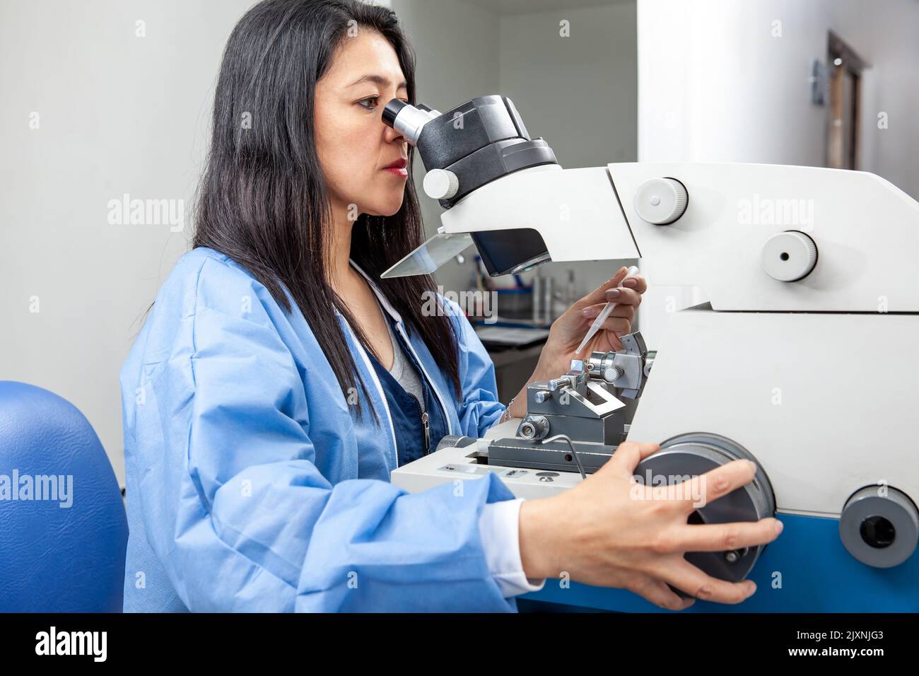 Young female scientist using an ultramicrotome to make sections for the ...