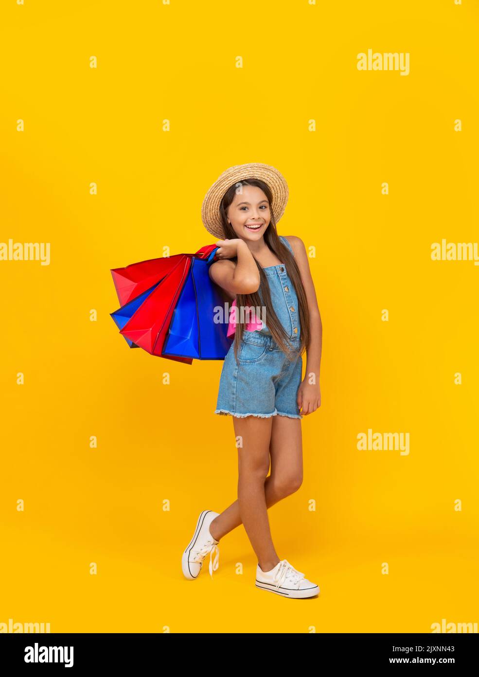 cheerful teen kid with shopping bags on yellow background. full length ...