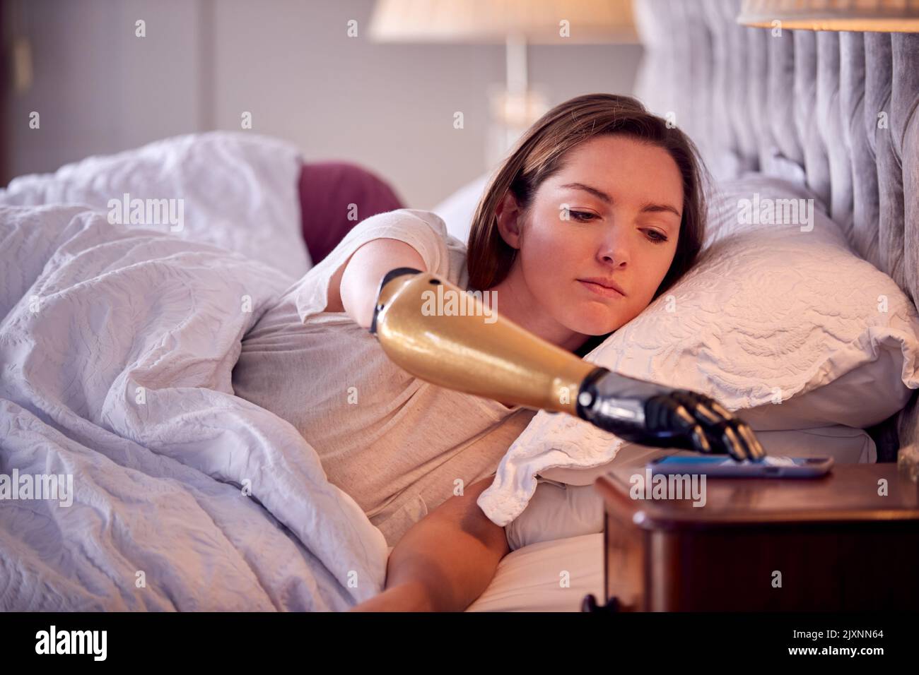 Couple With Woman With Prosthetic Arm Sleeping In Bed Before Being Woken By Mobile Phone Alarm ...