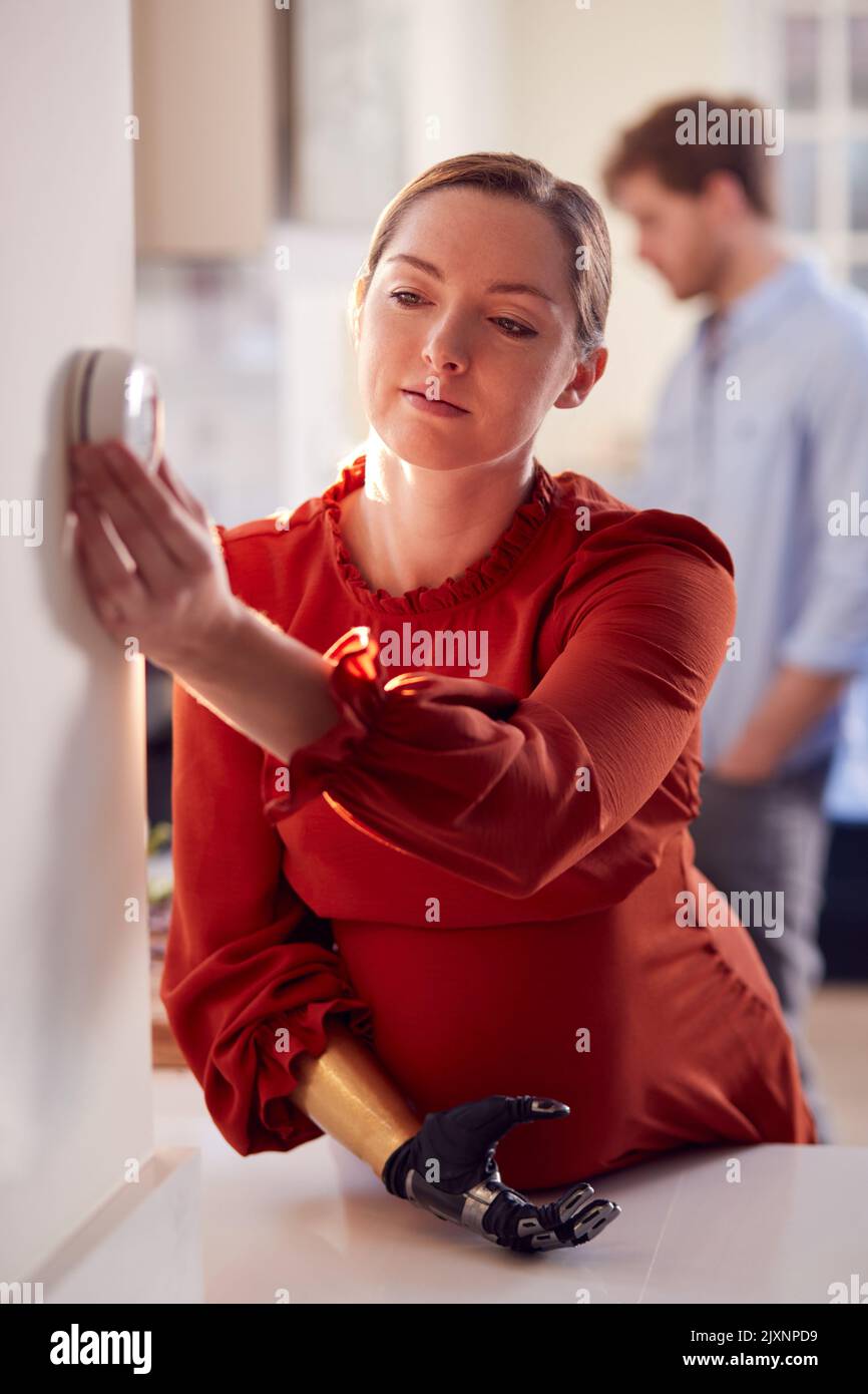 Pregnant Couple With Woman With Prosthetic Arm Turning Down Heating ...