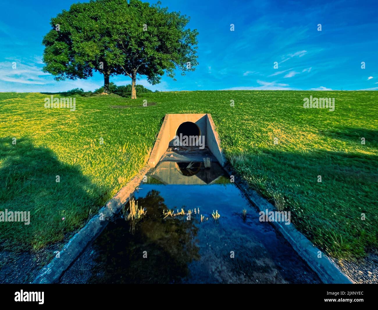 A rainwater drainage tunnel on a bright day surrounded by green meadows ...